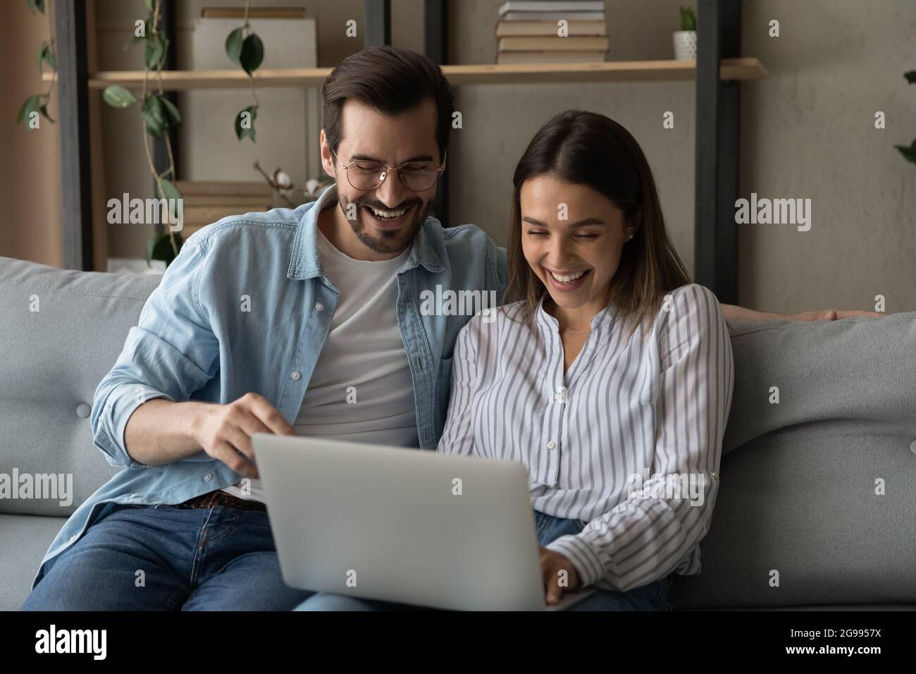 Laughing couple enjoy funny internet content while sit on sofa Stock ...