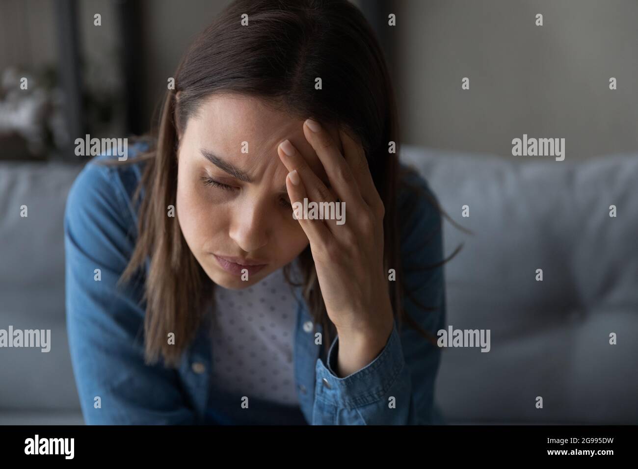 Closeup sad woman sit on sofa touch aching head Stock Photo - Alamy