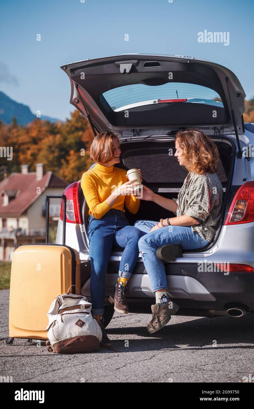 road trip - Two teenager smiling girls sitting in the boot. travel by ...