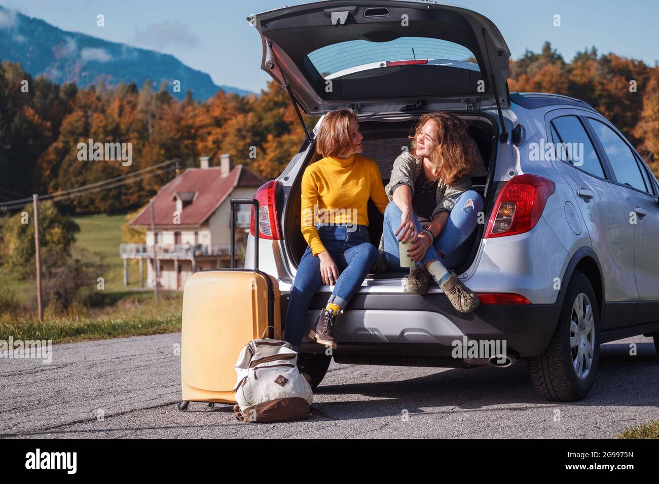 road trip - Two teenager smiling girls sitting in the boot. travel by ...