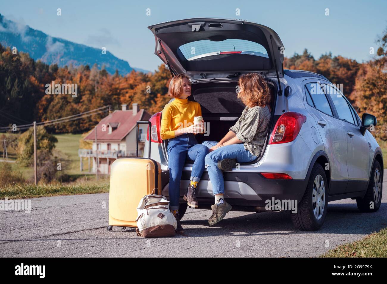 road trip - Two teenager smiling girls sitting in the boot. travel by ...