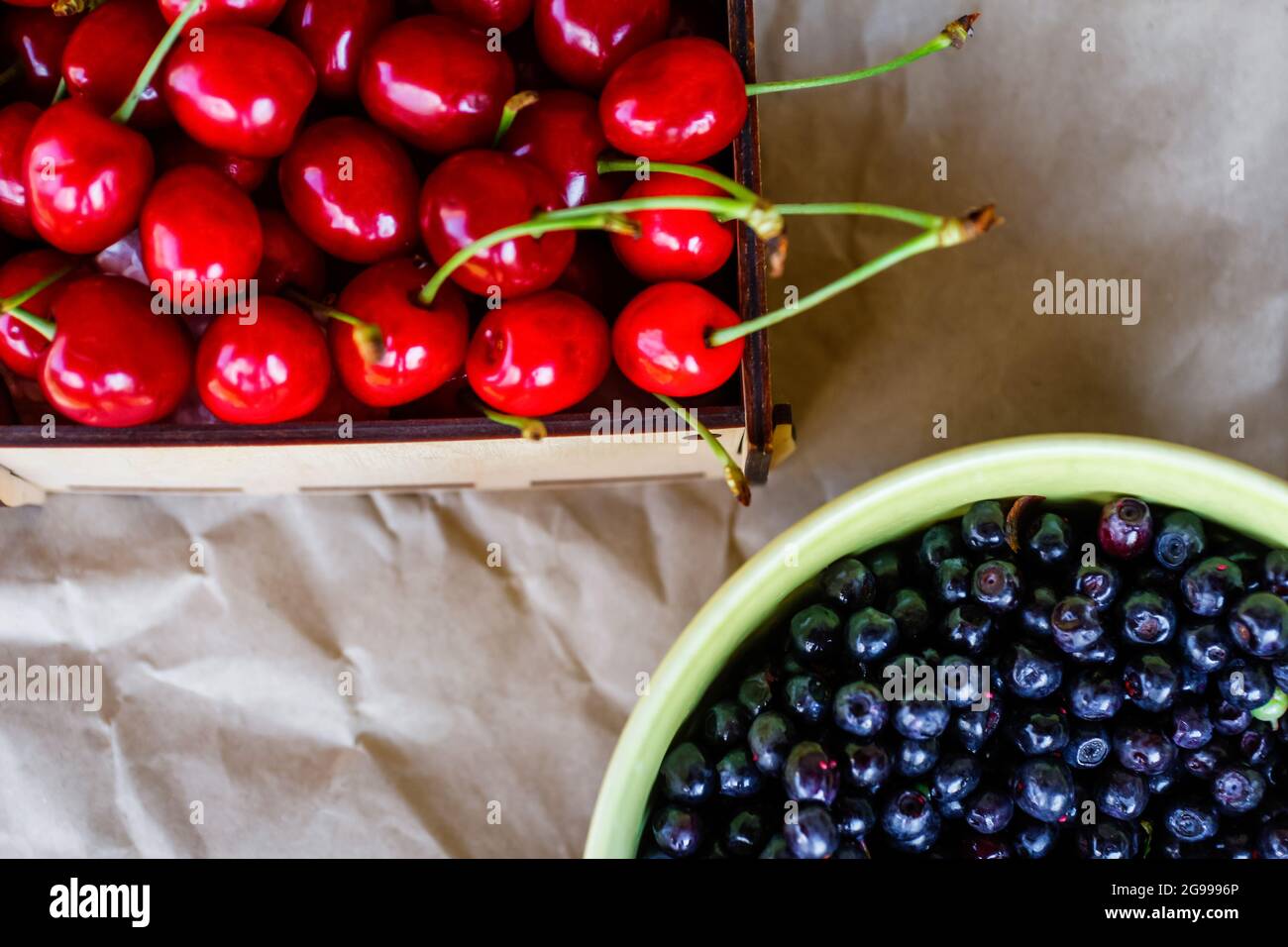 Cropped bowl of blueberries and box, crape of red sweet cherries with ...