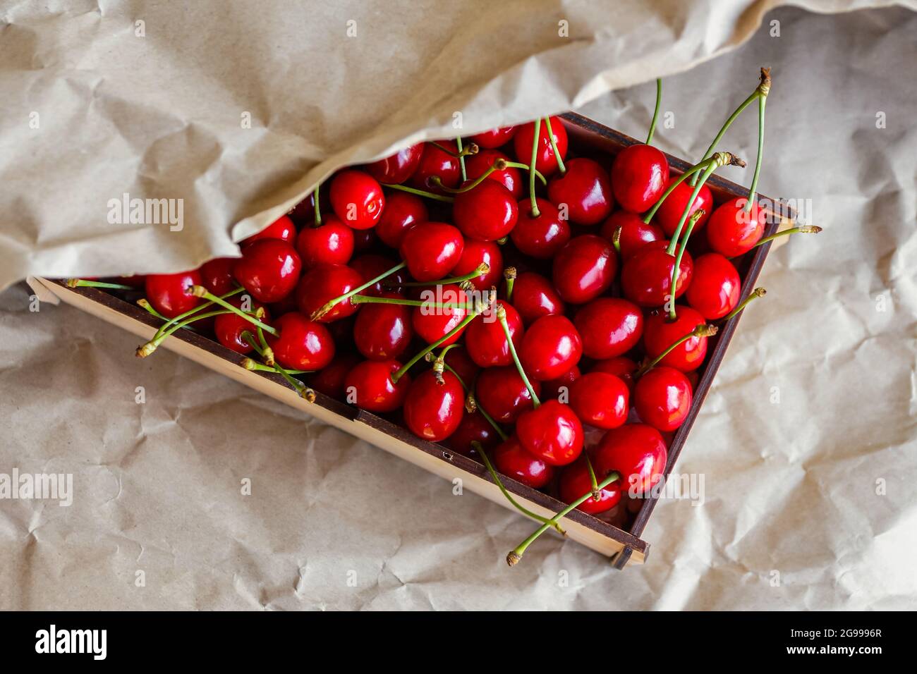 Cropped box, crape of dark red sweet cherries with tail on craft ...