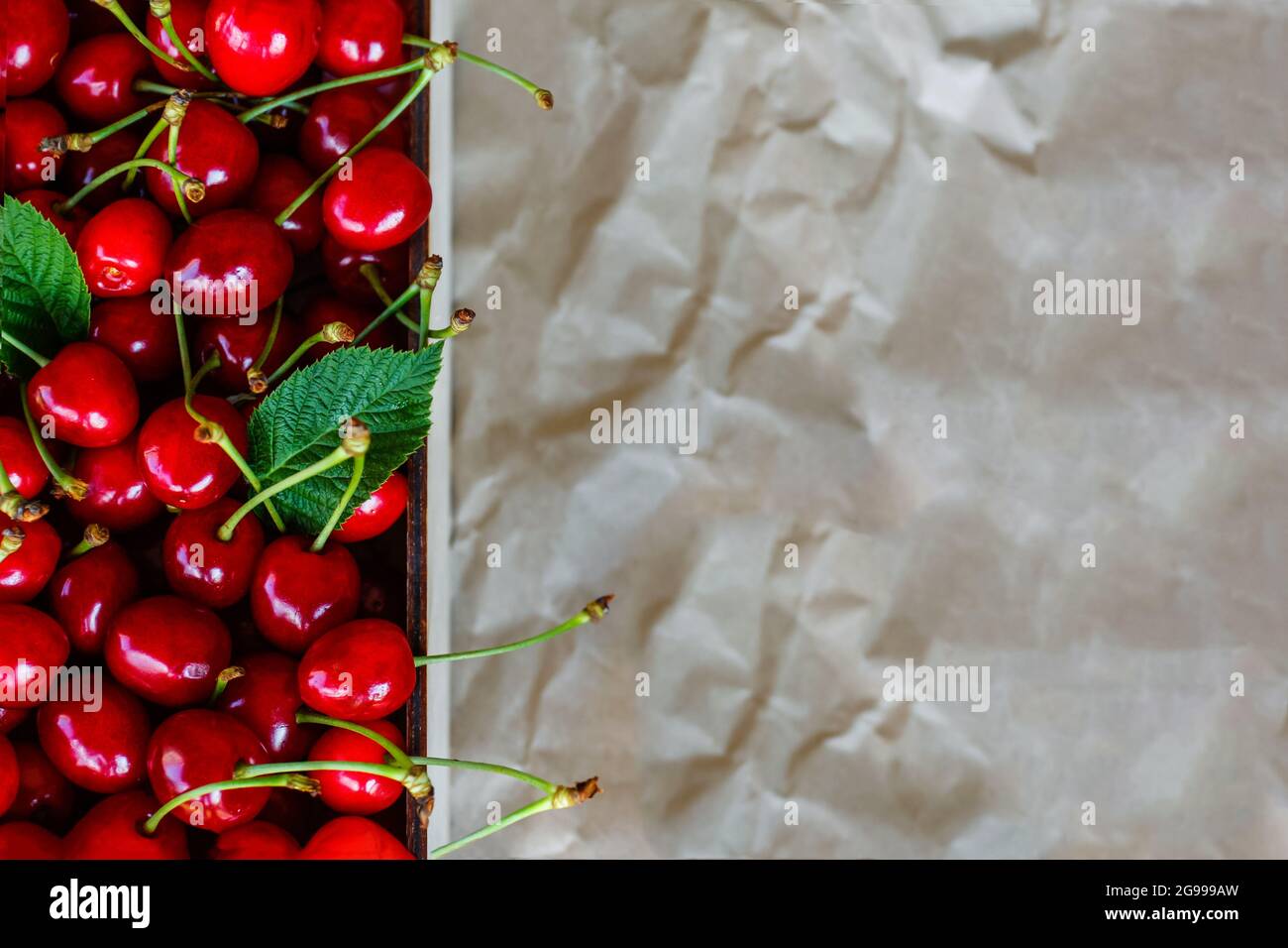 Cropped box, crape of dark red sweet cherries with tail and leaves on ...