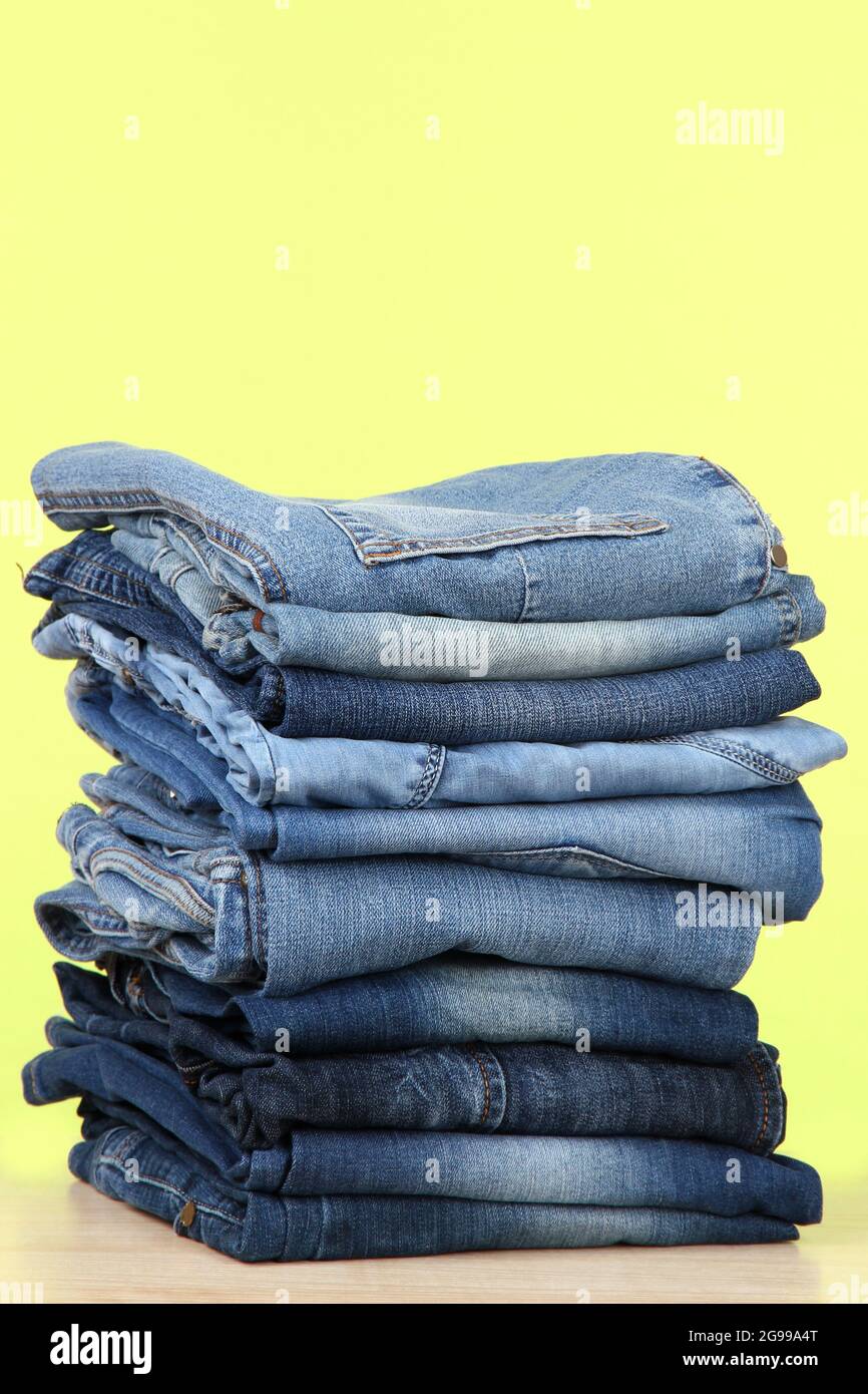 Many jeans stacked in a pile on green background Stock Photo - Alamy