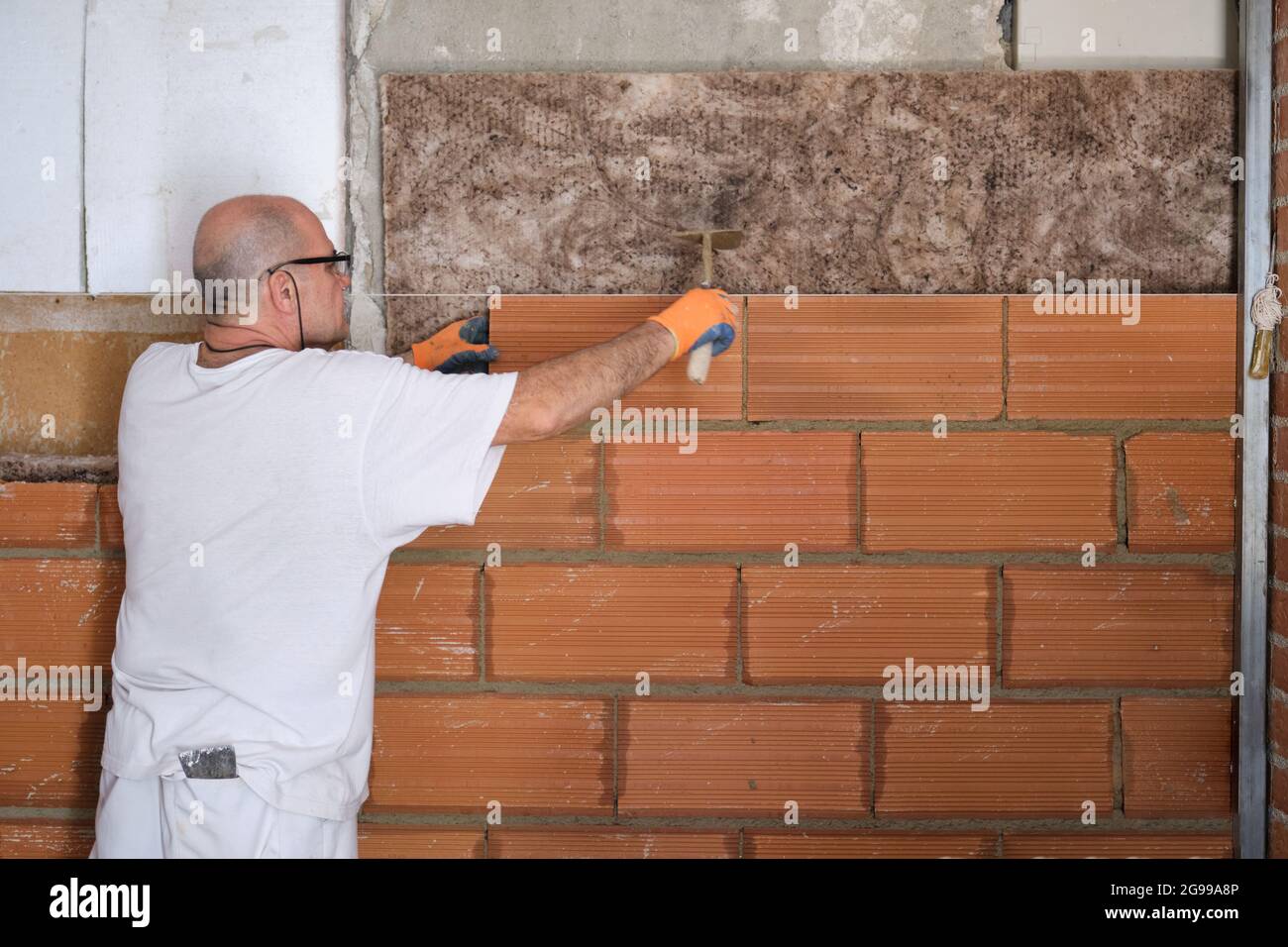 Construction worker laying bricks after placing an acoustic and thermal ...