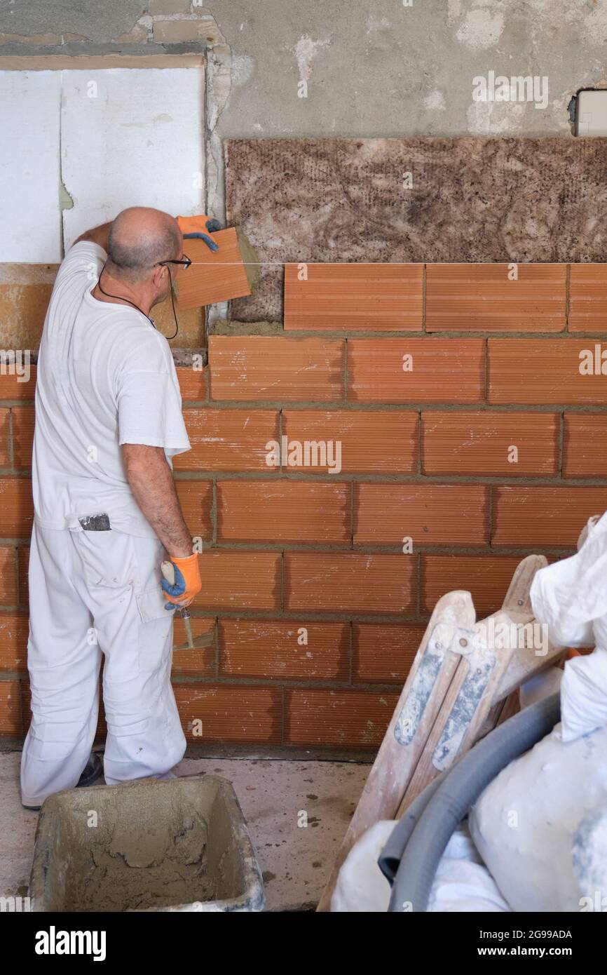 Construction worker laying bricks after placing an acoustic and thermal ...