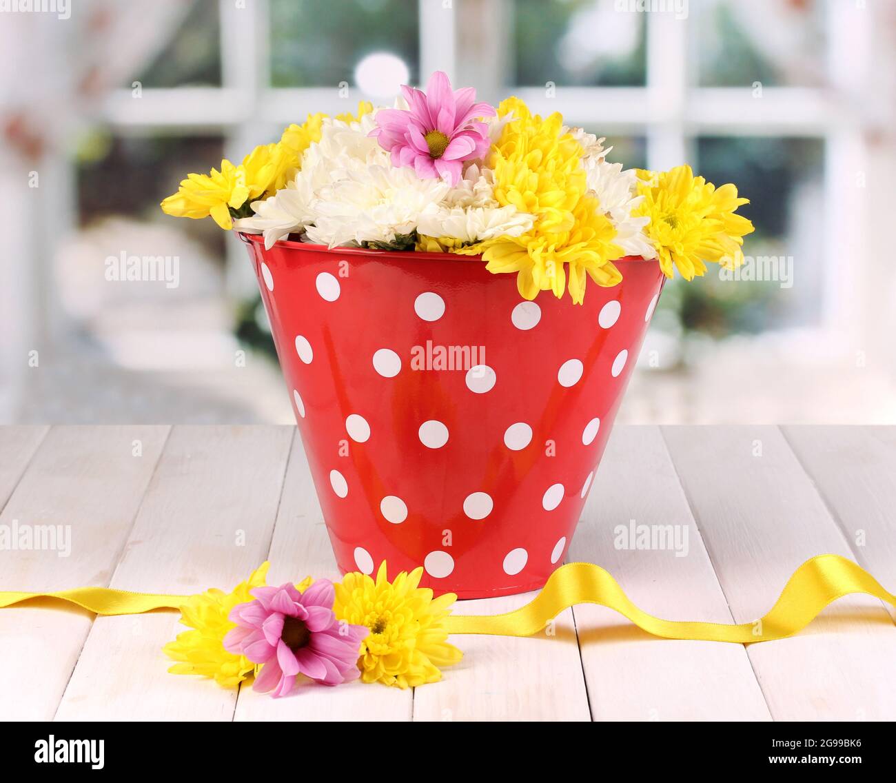 Red pail of peas with flowers on white wooden table on window ...