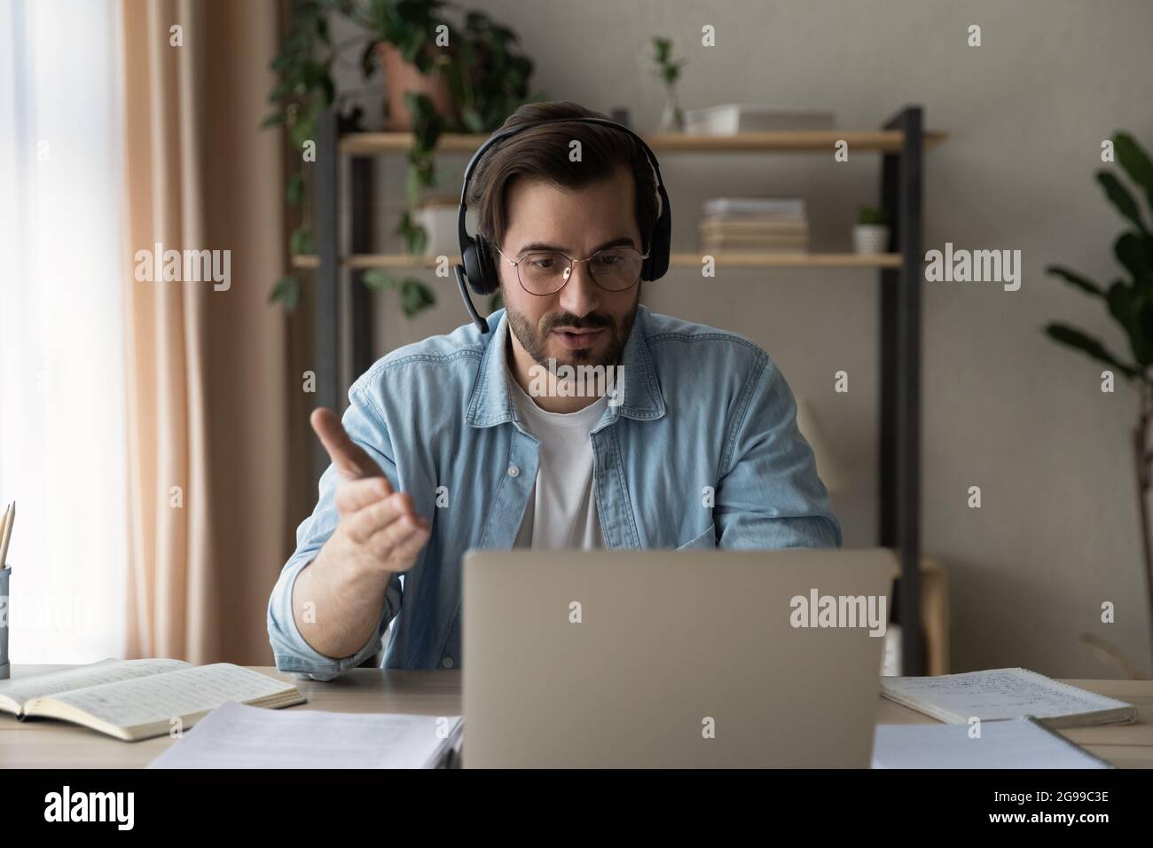 Man wear headset looks at laptop screen and talking Stock Photo - Alamy
