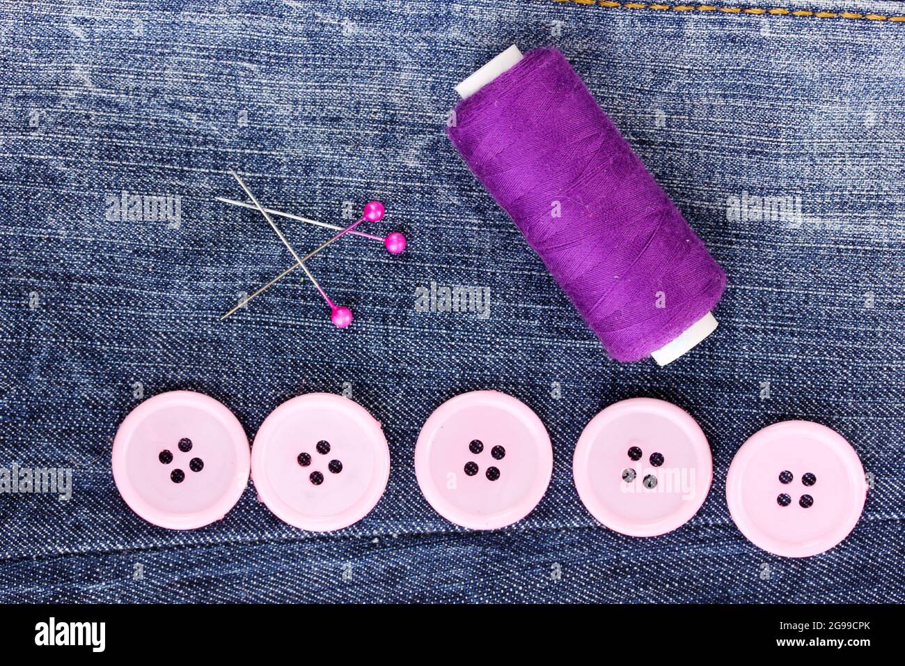 Colorful sewing buttons with thread on jeans closeup Stock Photo - Alamy
