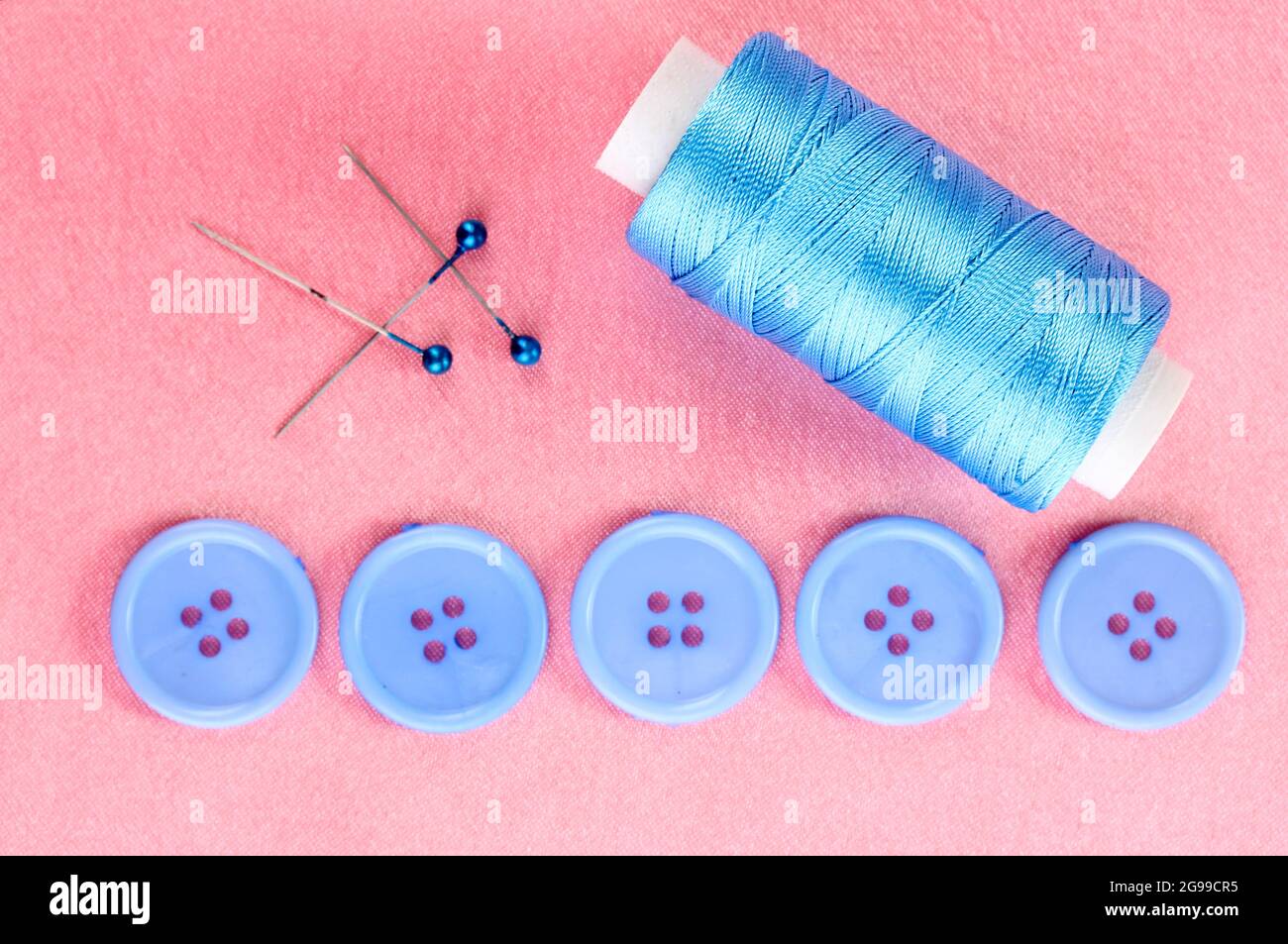 Colorful sewing buttons with thread on pink fabric Stock Photo - Alamy