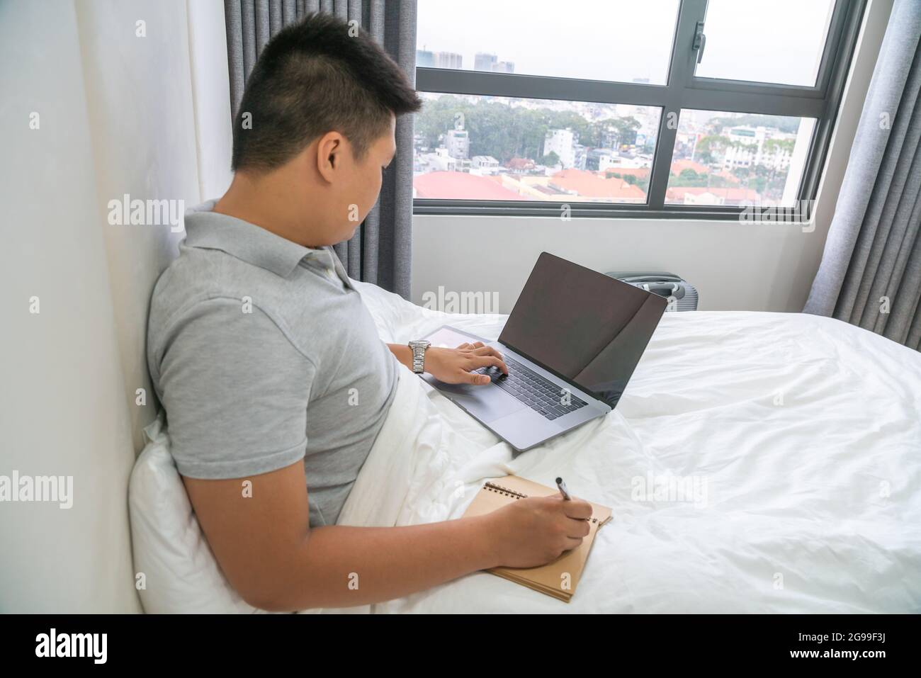 Using laptop and writing notes in bedroom Stock Photo - Alamy
