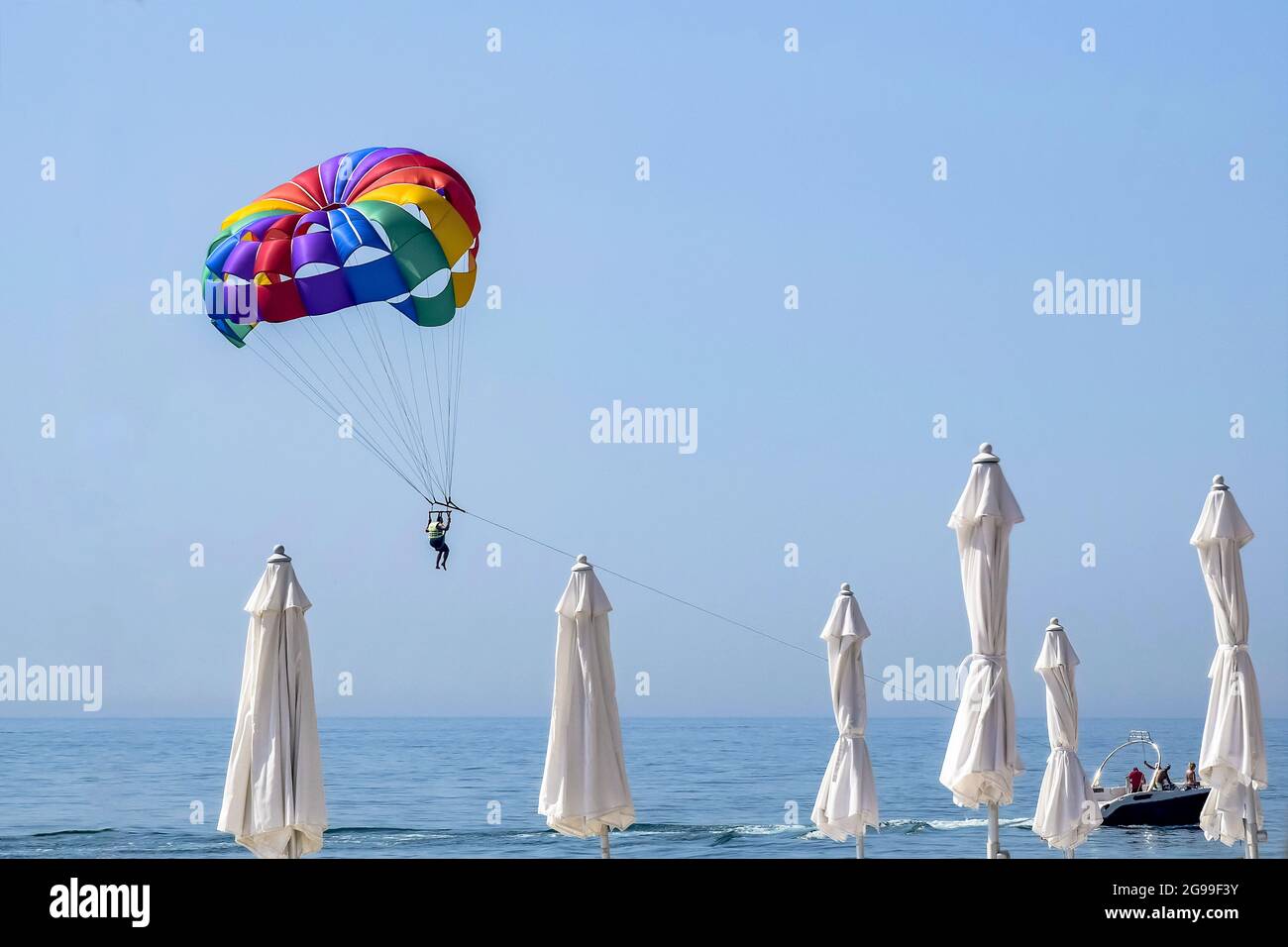Multi-colored parachute with a man on the background of the sea and ...