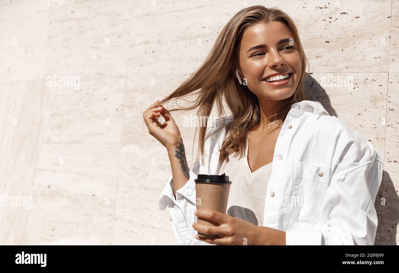 Portrait of smiling blond girl, woman drinking takeaway coffee on ...