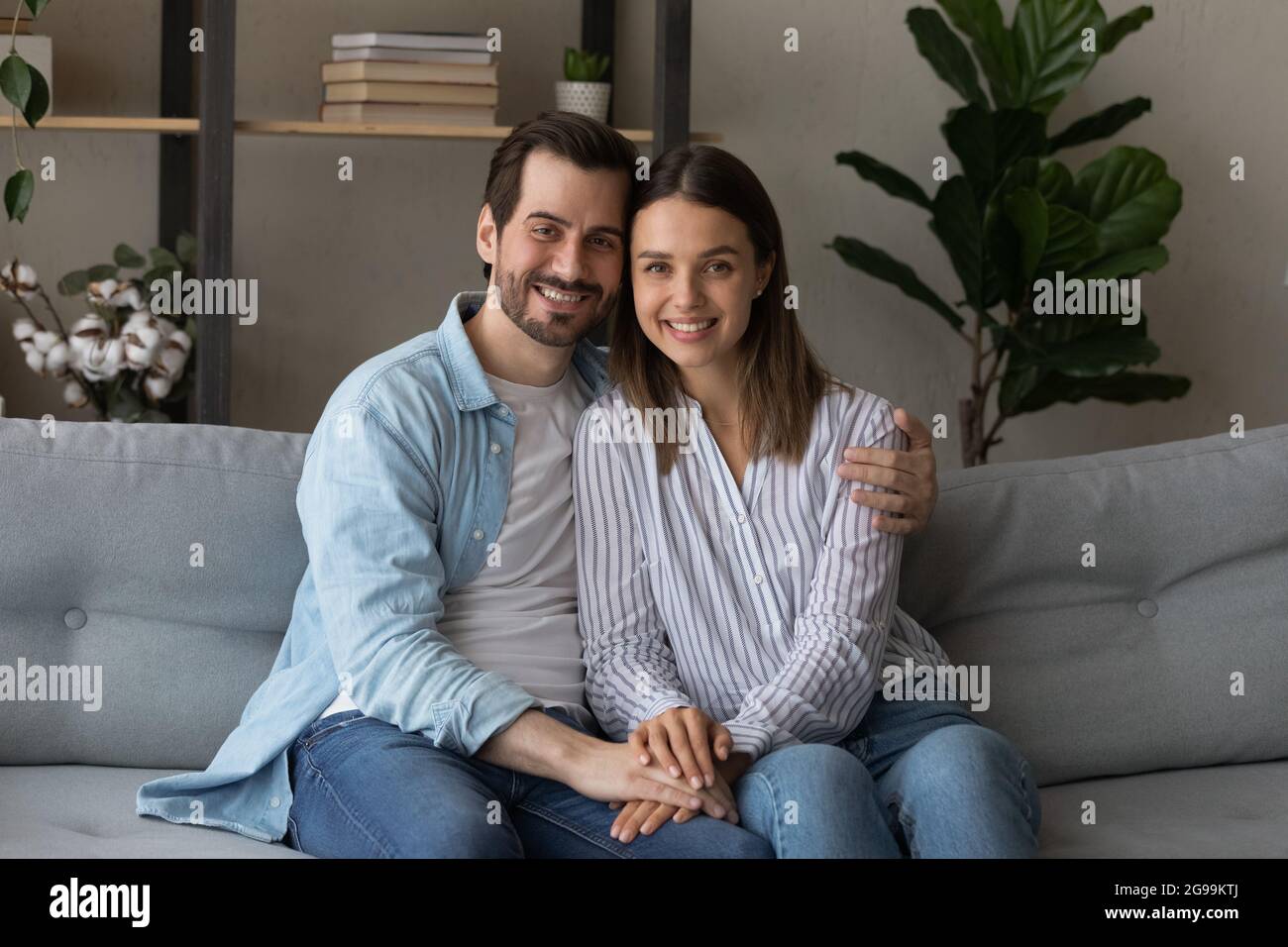 Beautiful married couple sit on sofa smile look at camera Stock Photo ...