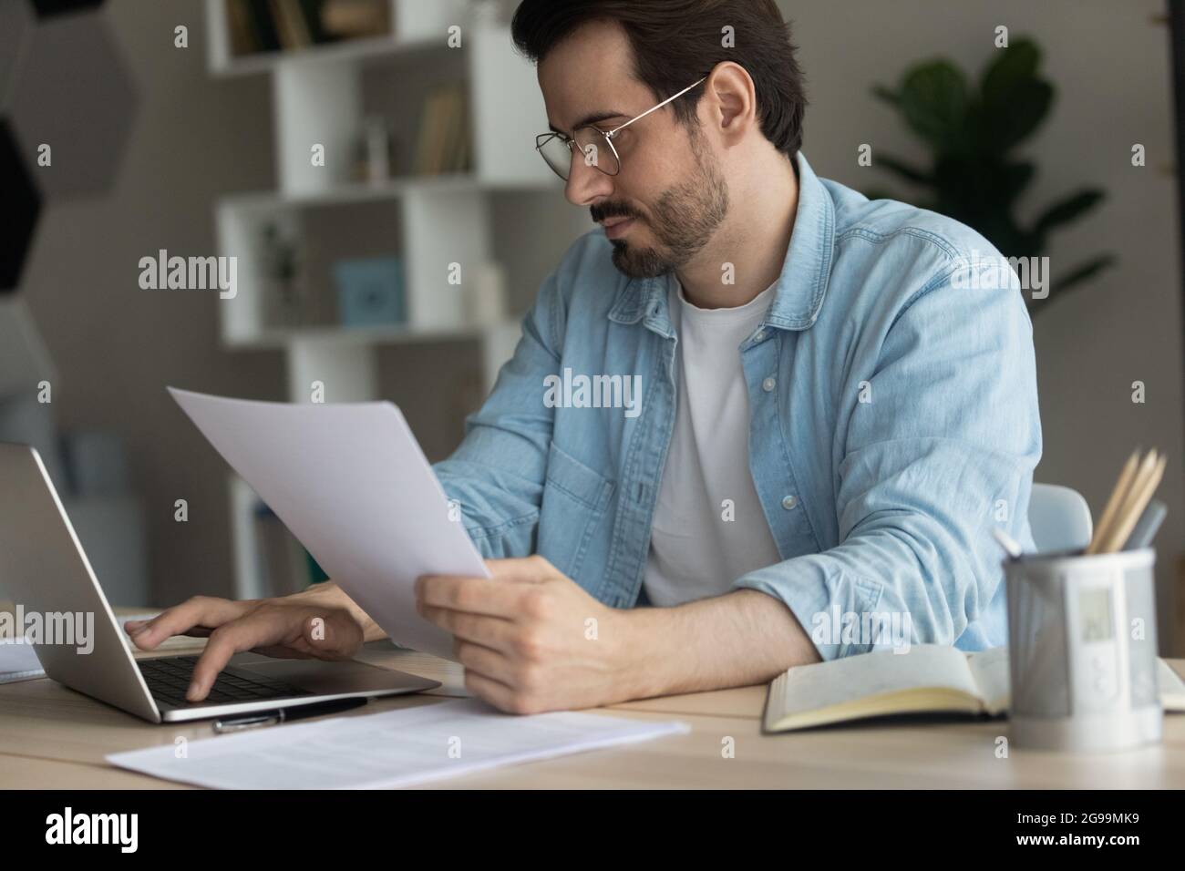 Focused businessman doing paperwork working online on laptop Stock ...