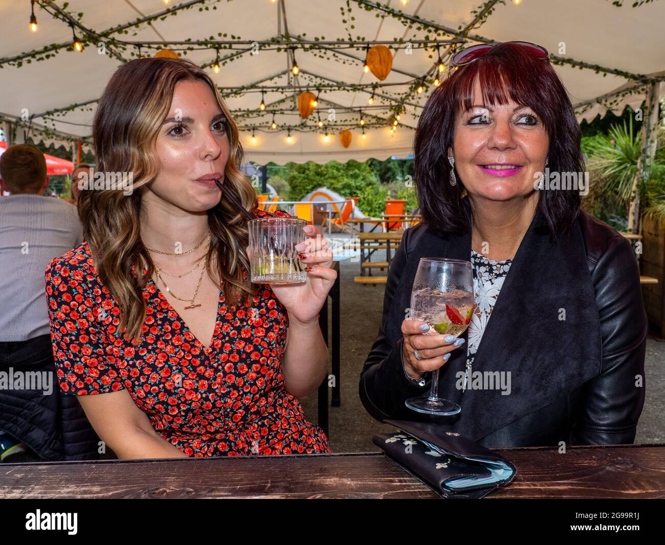 Two brunette women drinking alcohol in the outside seating area of a ...