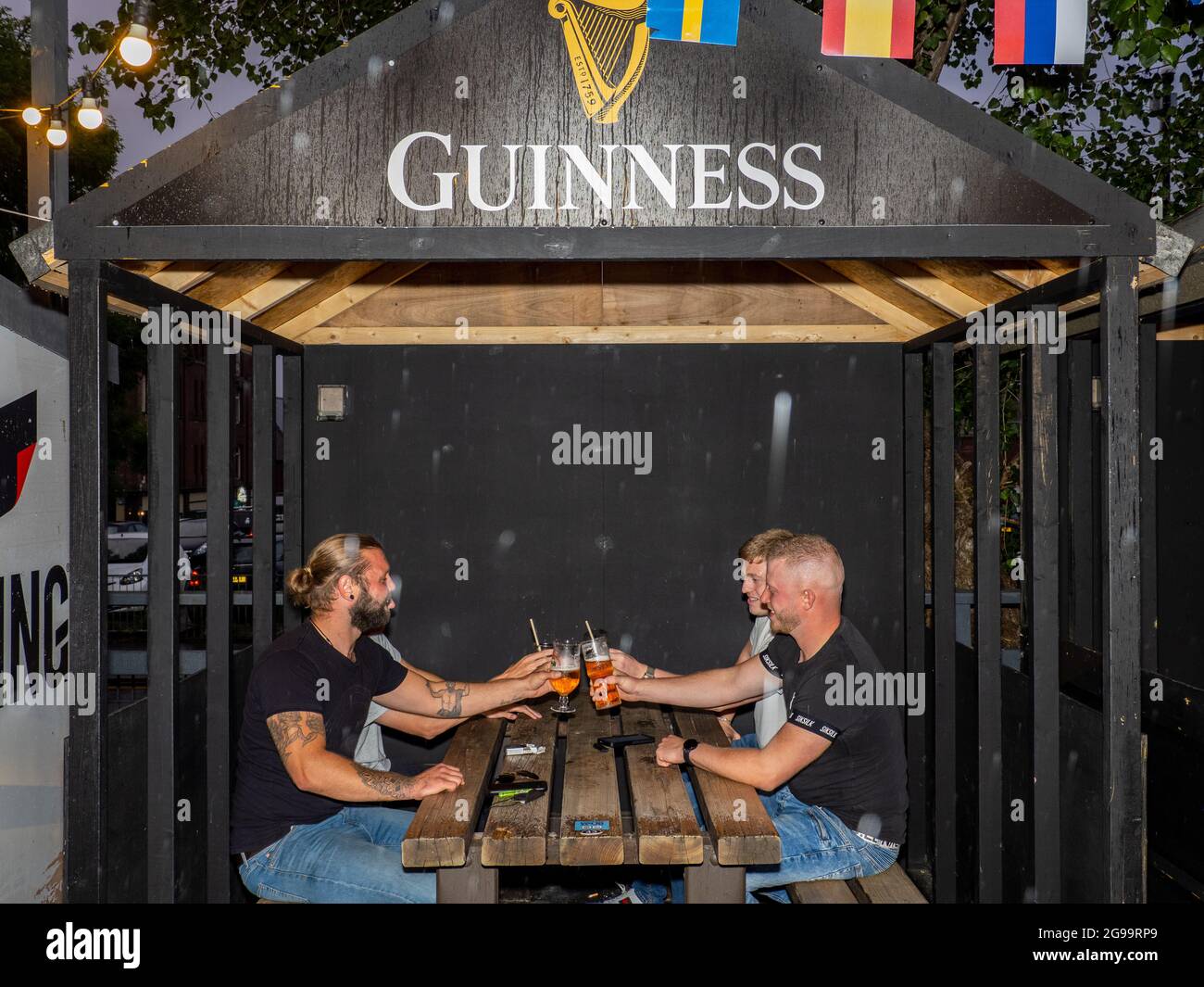 Four male friends drink in an outside booth on a Friday night at ...