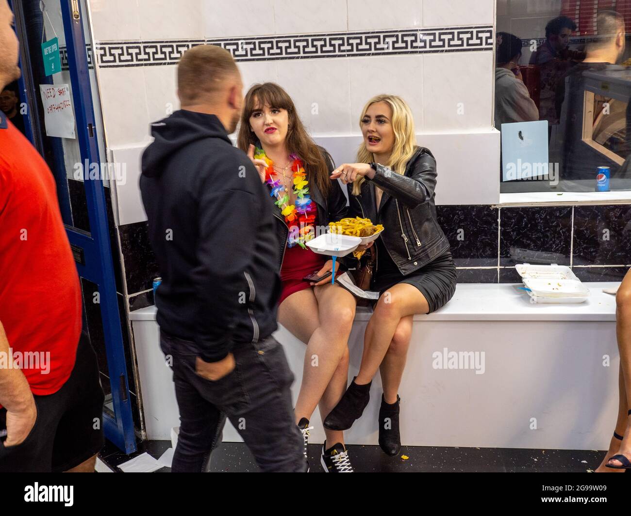 Young women eat fast food in a take-away after Friday night out in ...