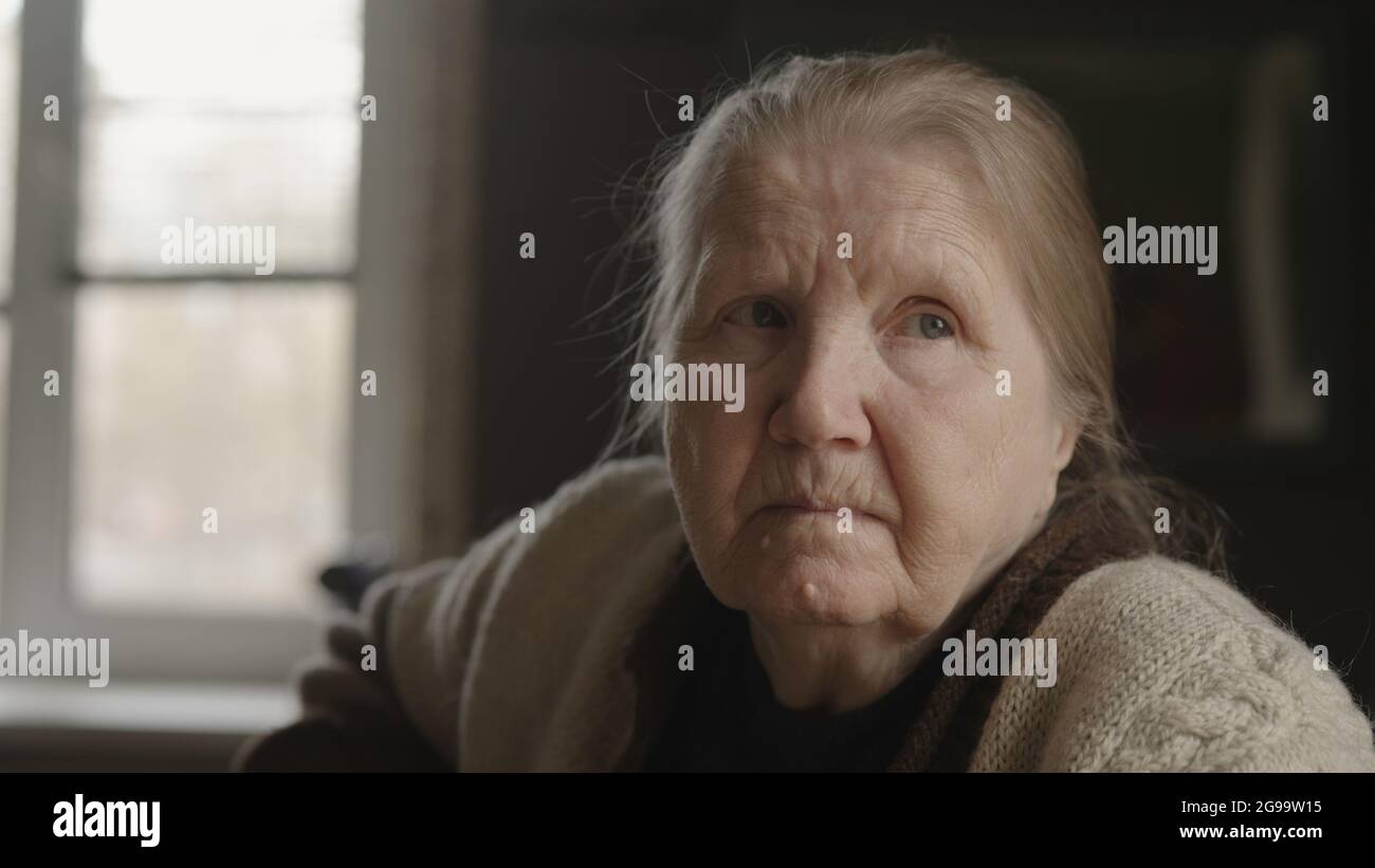 Senior woman sitting indoor with soft window light, wide photo Stock ...