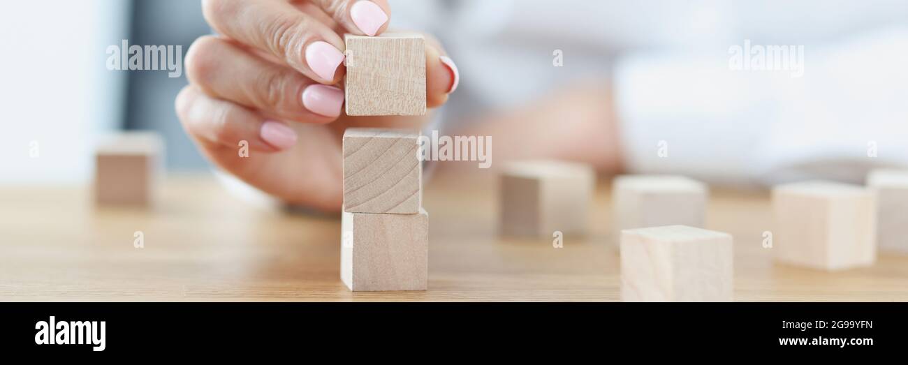 Female hand builds tower from wooden cubes Stock Photo - Alamy