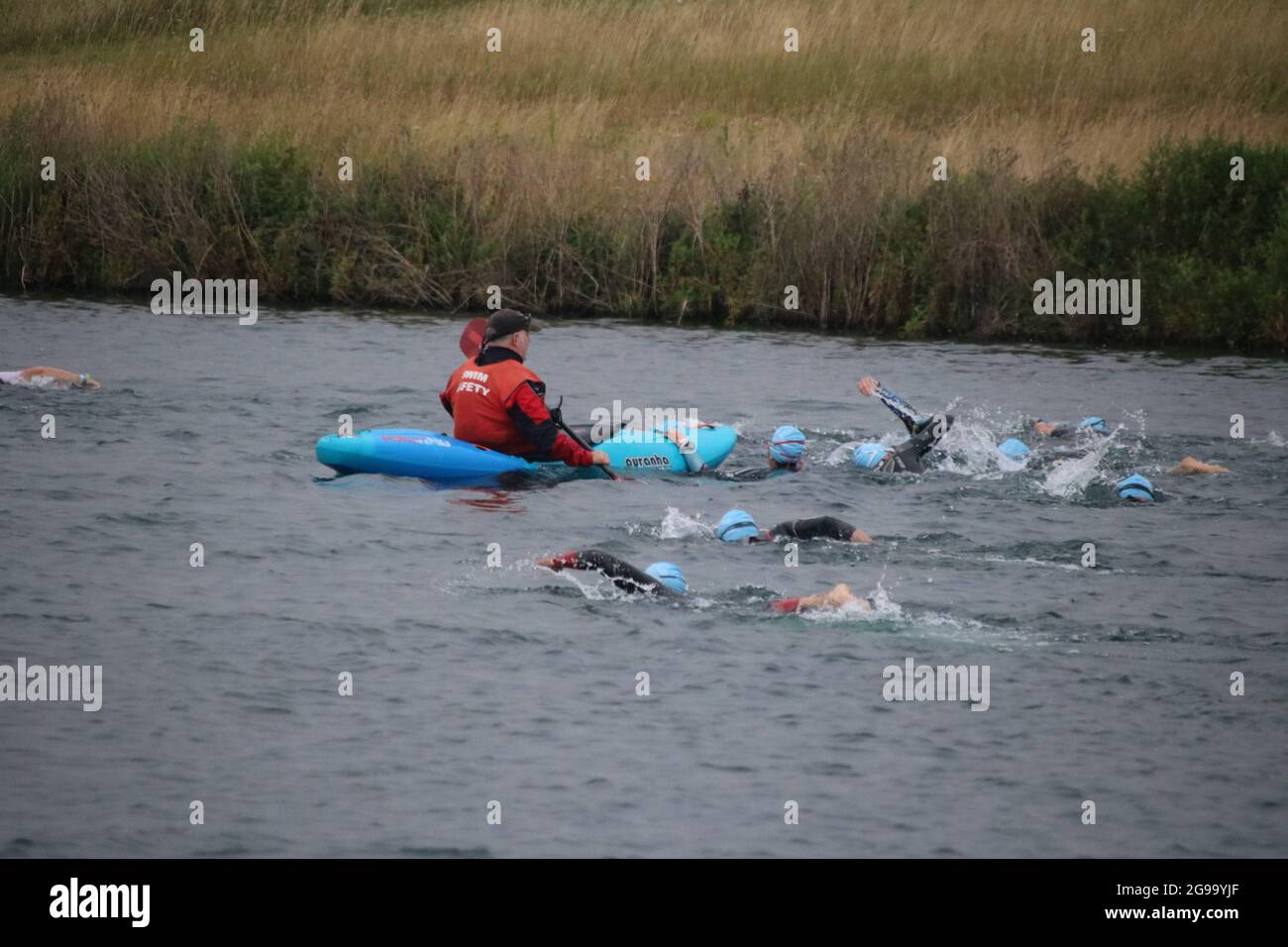 triathlon swimmer in difficulty being rescued by rescue kayak Stock ...