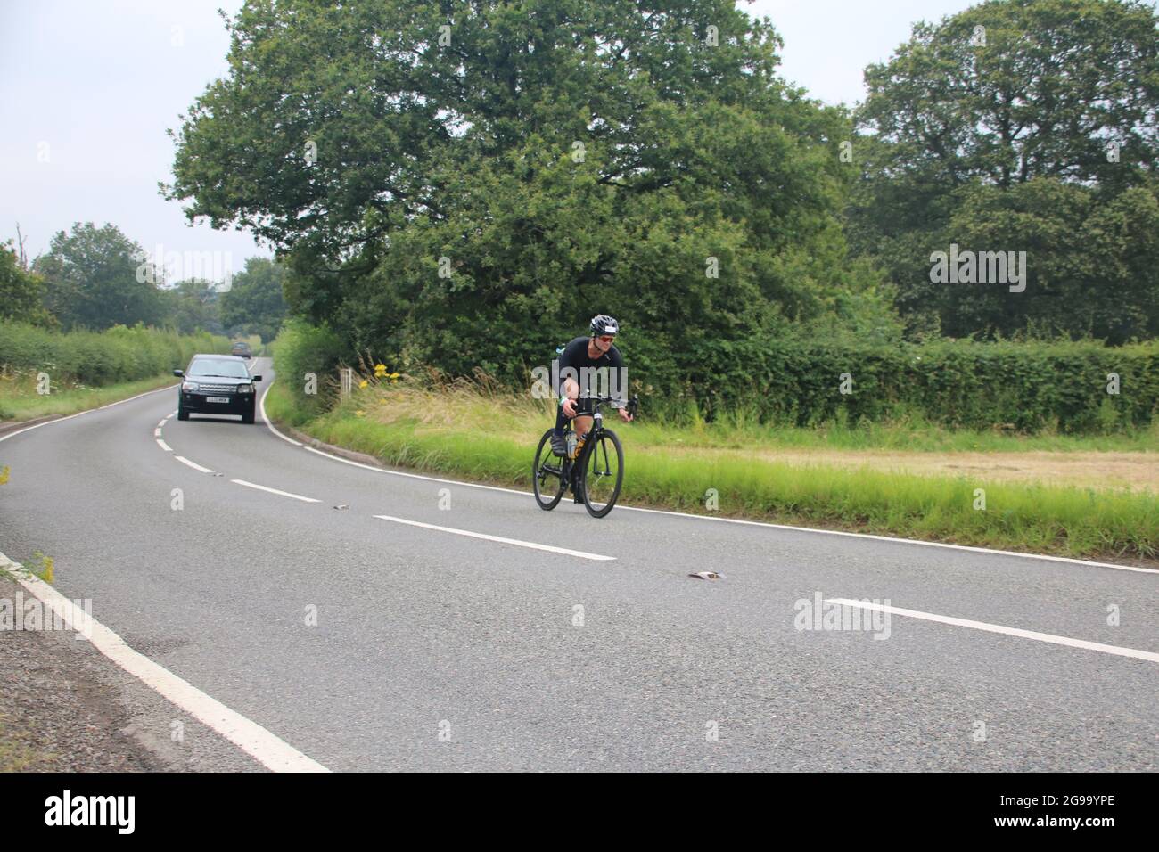 one cyclist in front of a car on a road in the Surrey Hills Stock Photo ...