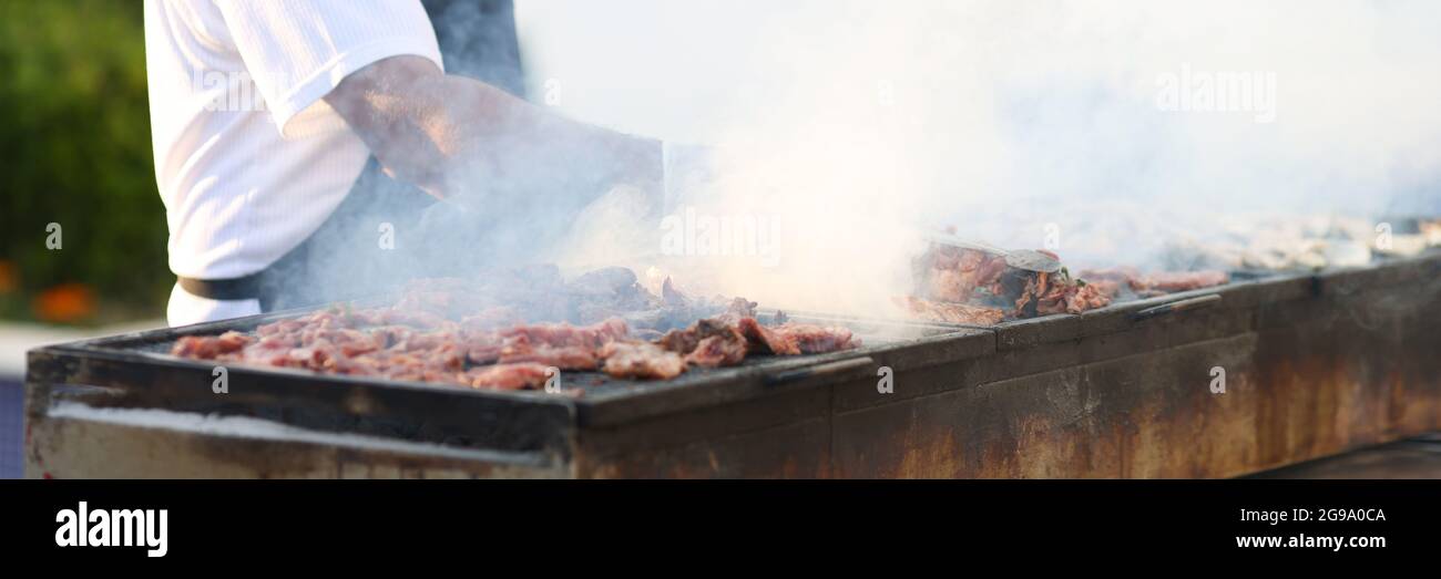 Cook prepares meat on coals in the open air Stock Photo - Alamy