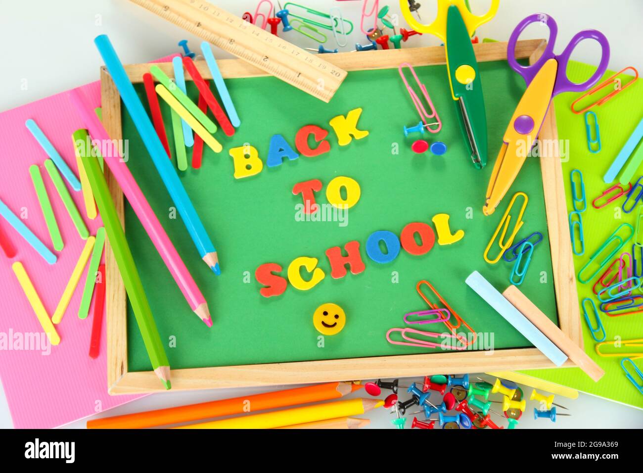 Small chalkboard with school supplies on white background. Back to ...