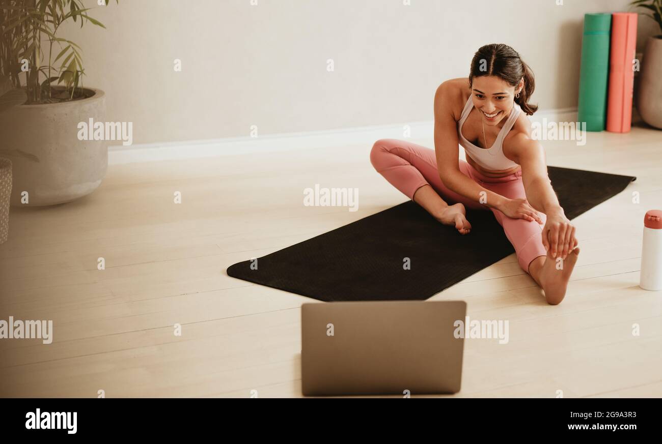 Female fitness trainer teaching leg stretching exercises online on ...