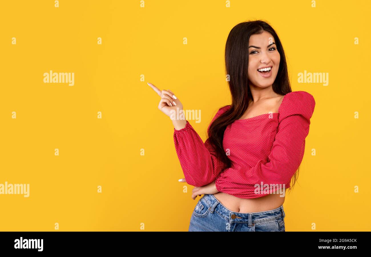 Special offer concept. Excited armenian lady pointing finger at empty ...