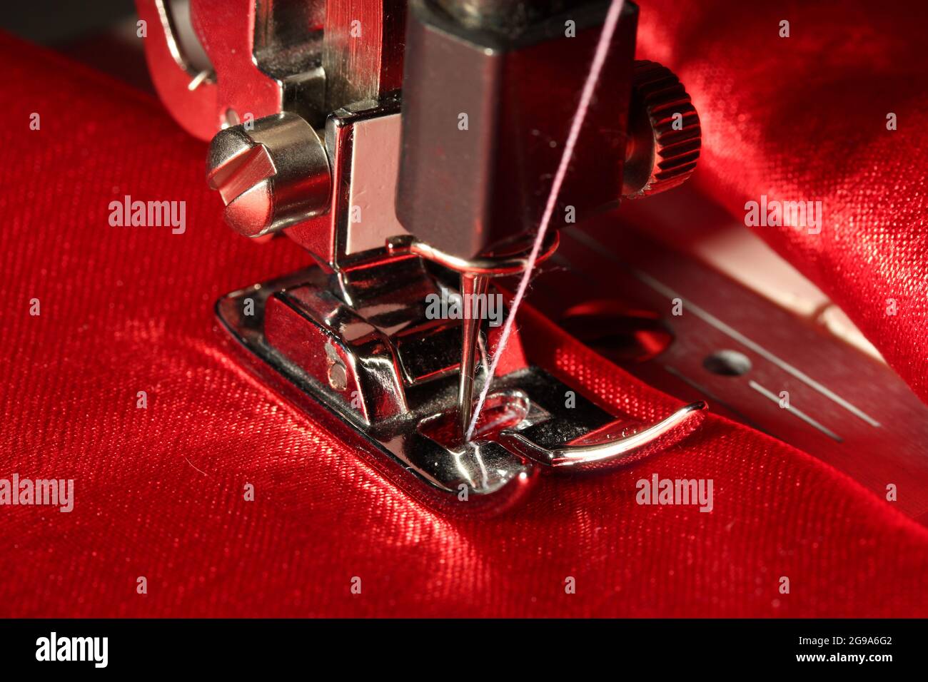Sewing machine with red cloth closeup Stock Photo - Alamy
