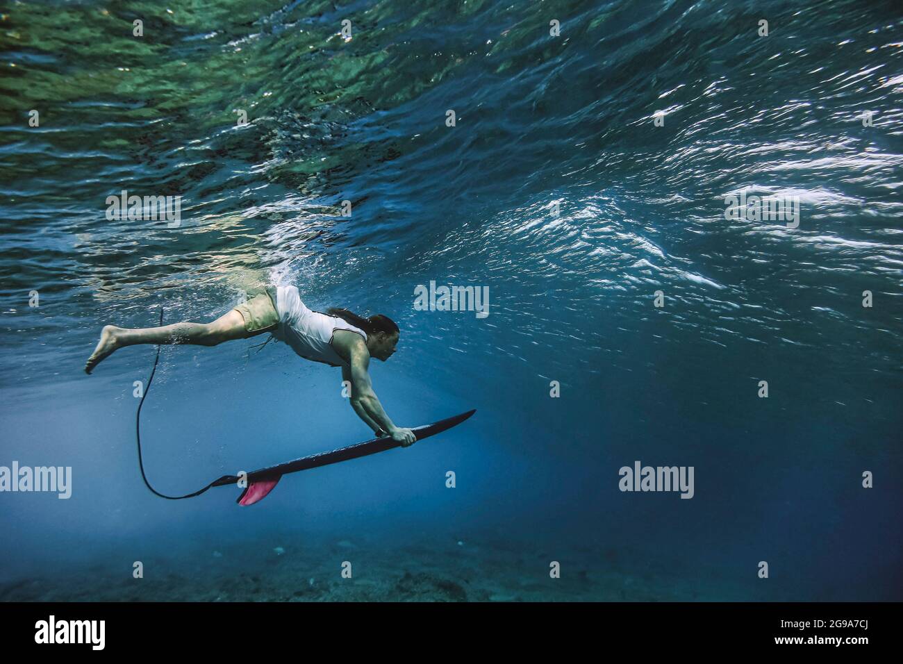 Male surfer holding surfboard while diving undersea at Maldives Stock ...