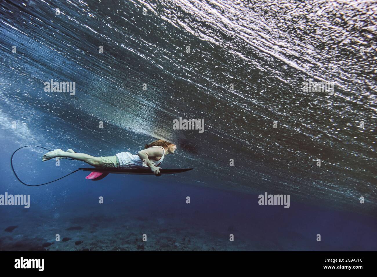 Male surfer holding surfboard while diving undersea at Maldives Stock ...