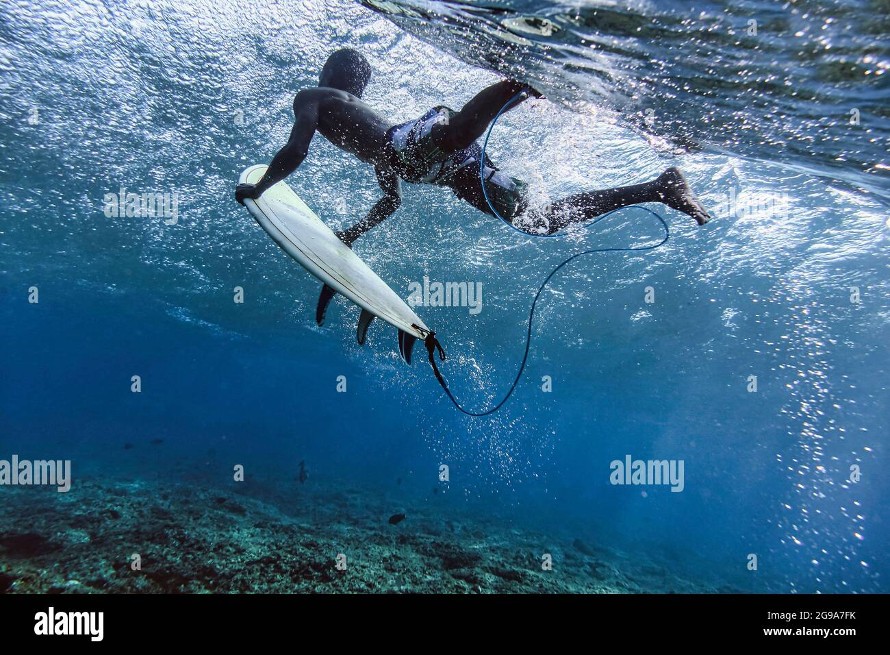 Male surfer holding surfboard while diving undersea at Maldives Stock ...