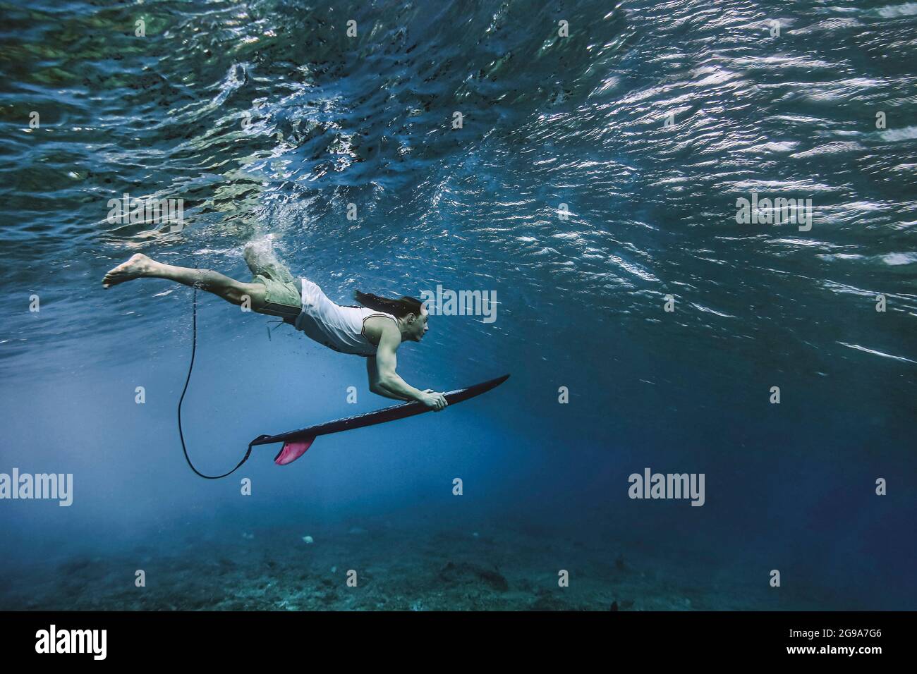 Male surfer holding surfboard while diving undersea at Maldives Stock ...