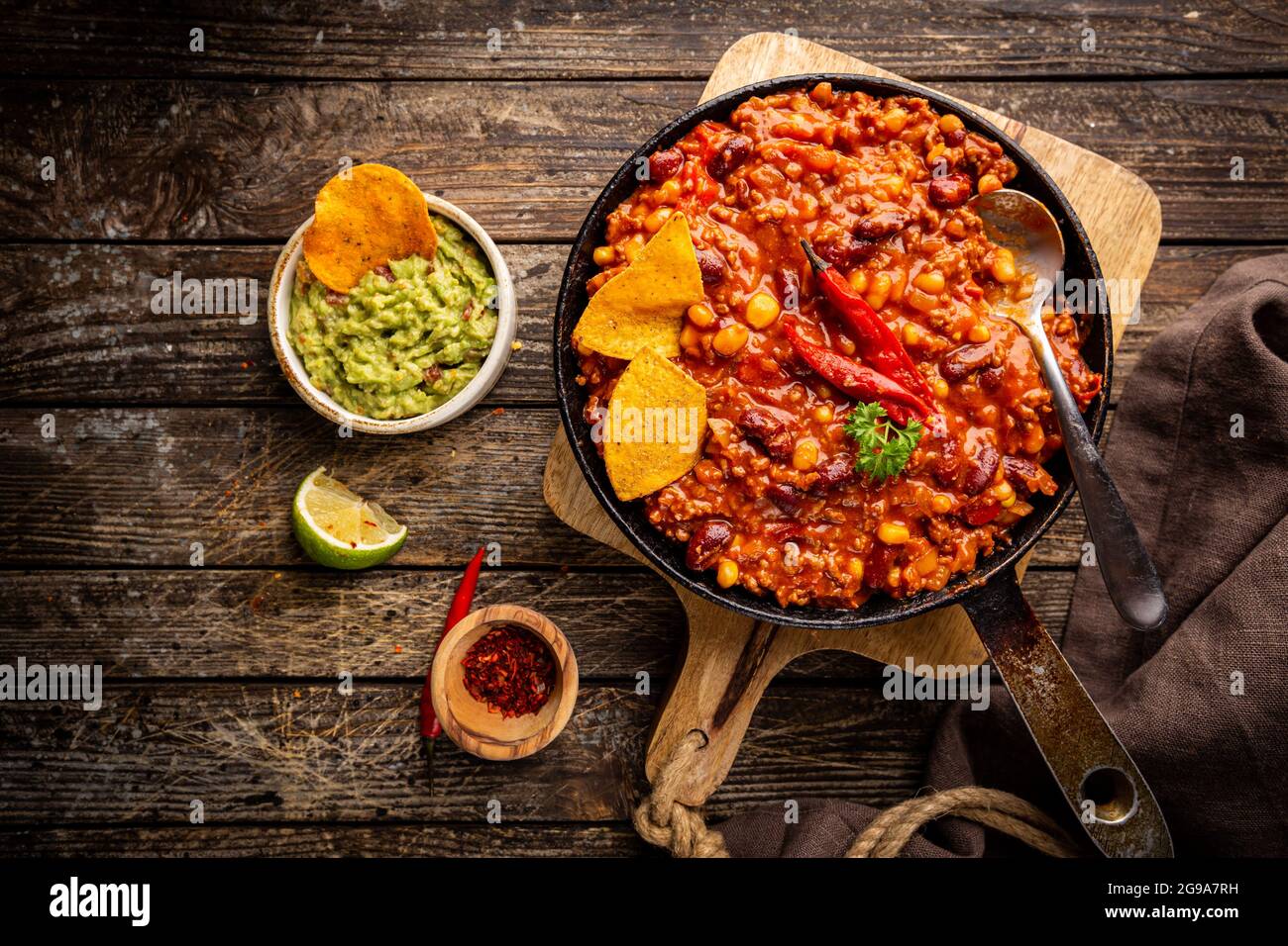 Mexican hot chili con carne in a pan with tortilla chips on dark ...