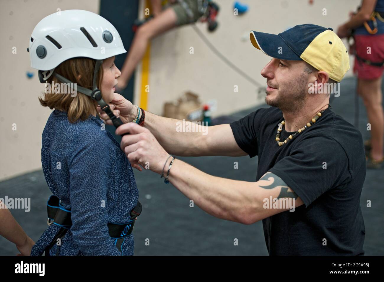 climbing coach helping girl adjusting climbing helmet Stock Photo - Alamy