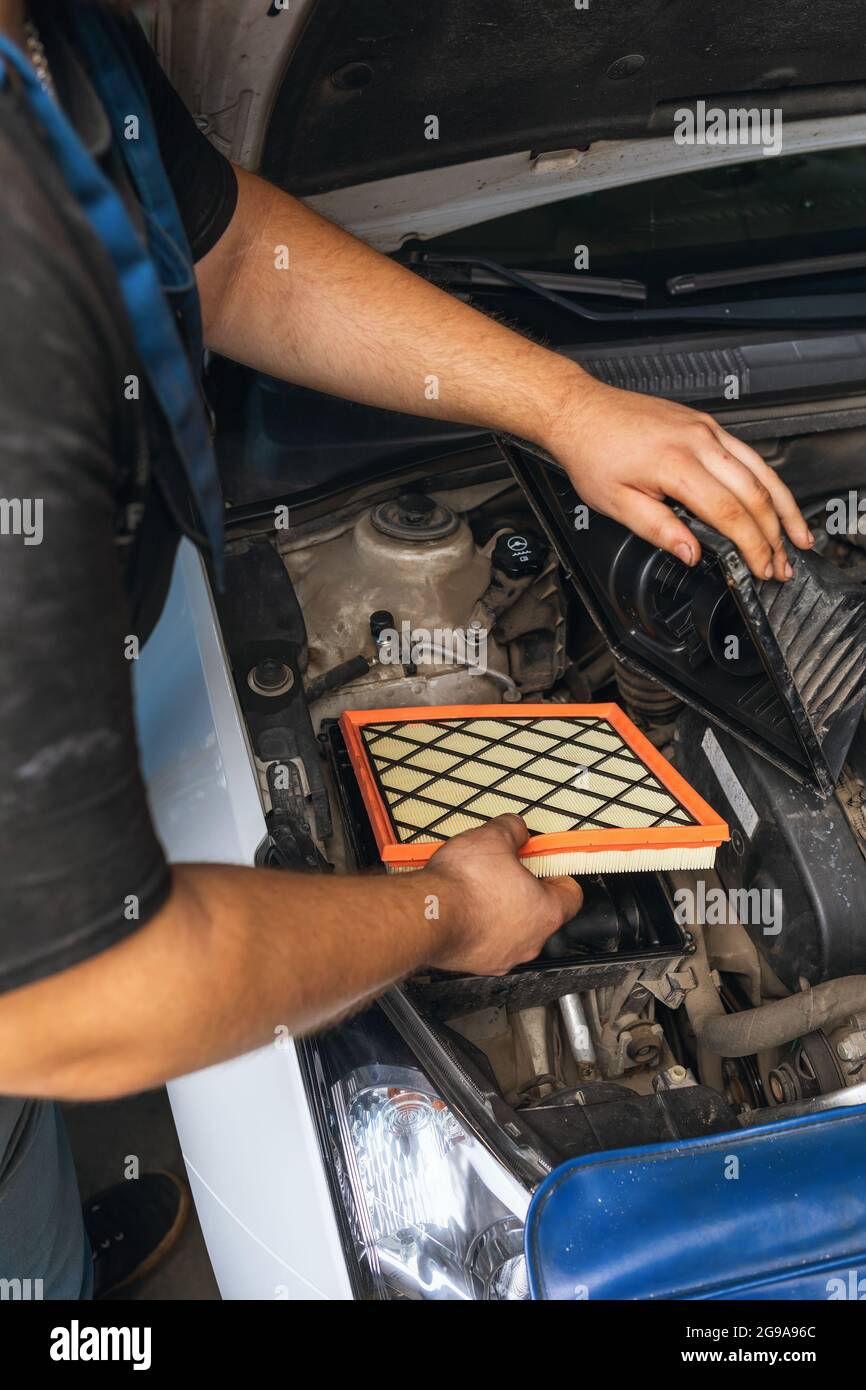 An auto mechanic installs a new engine air filter in a passenger car ...