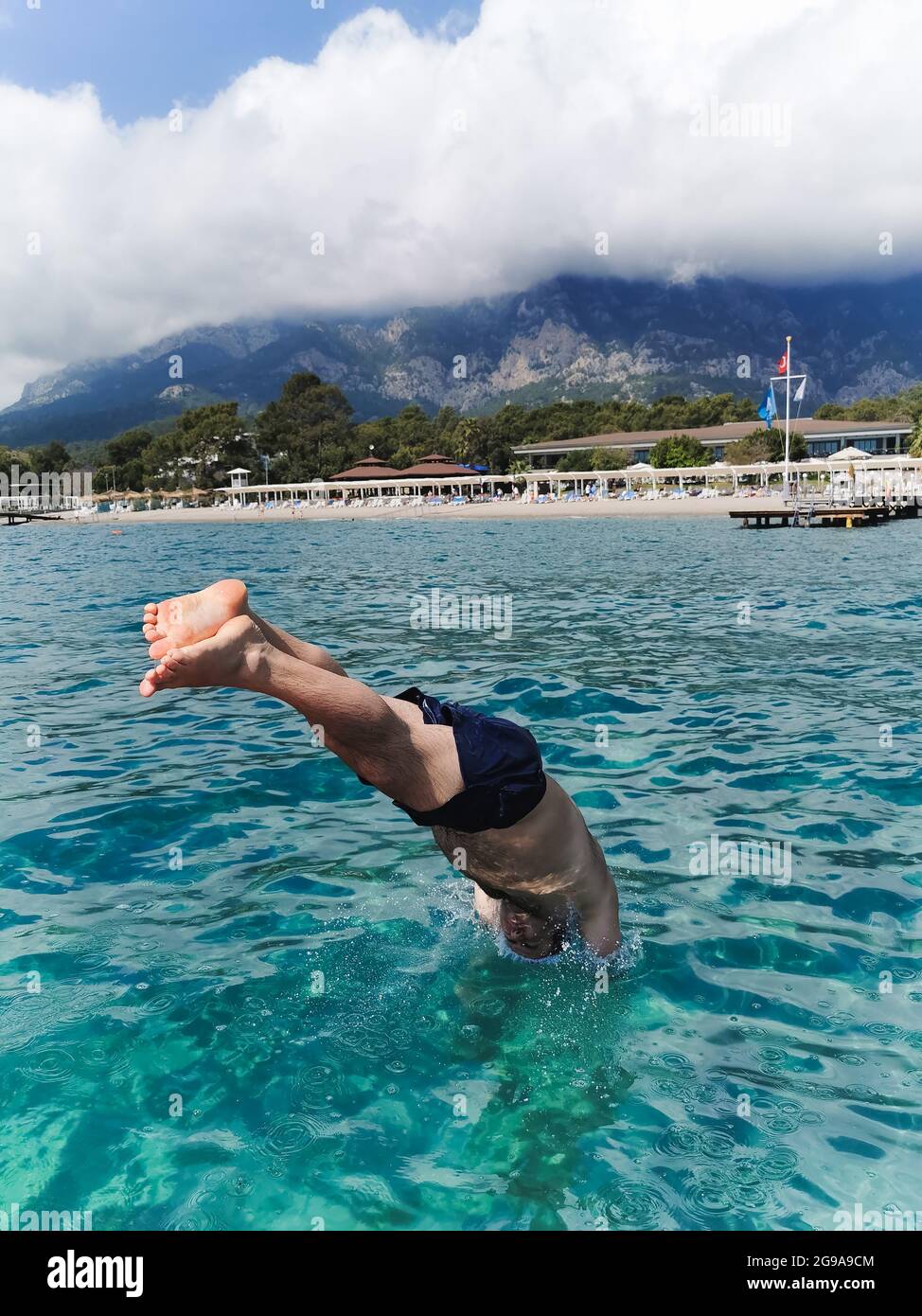 A man dives in shorts dives from a platform into the sea Stock Photo ...