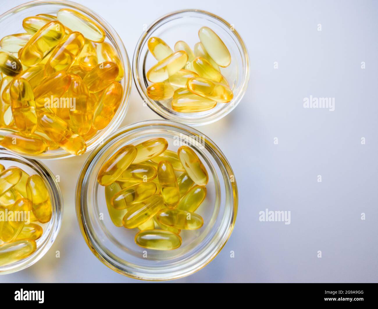 Fish oil capsules on a glass plate. A lot of vitamin omega 3 on a white ...