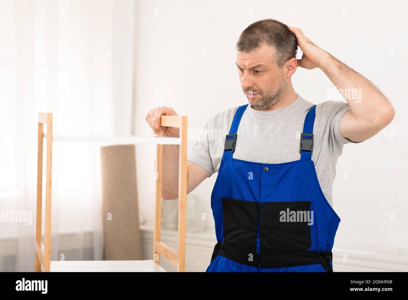 Confused male worker assembling shelf hi-res stock photography and ...