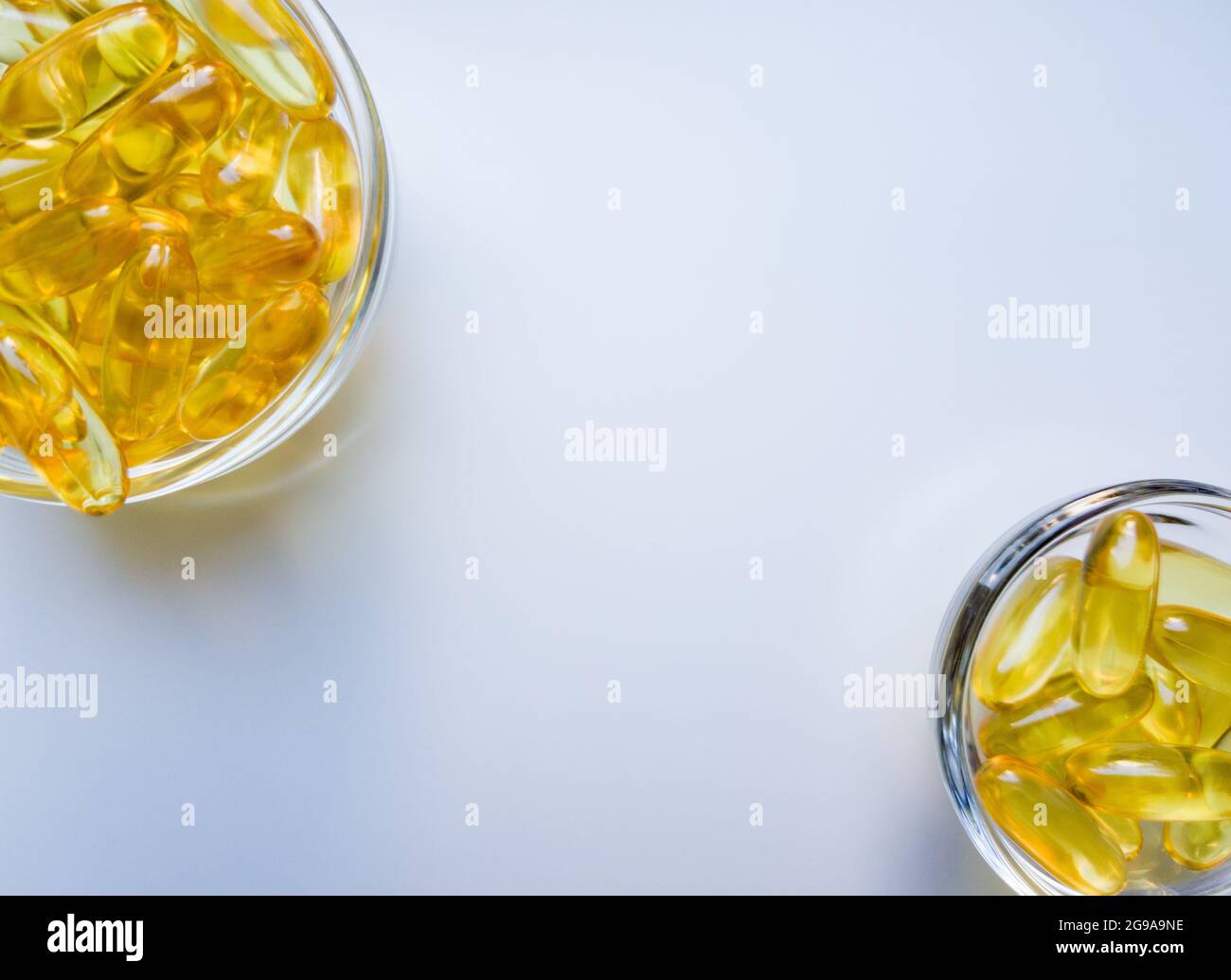 Fish oil capsules on a glass plate. A lot of vitamin omega 3 on a white ...