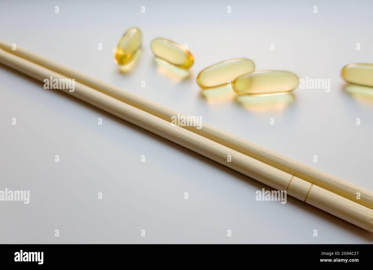 Fish oil capsules with Chinese chopsticks. Omega 3 on a white ...
