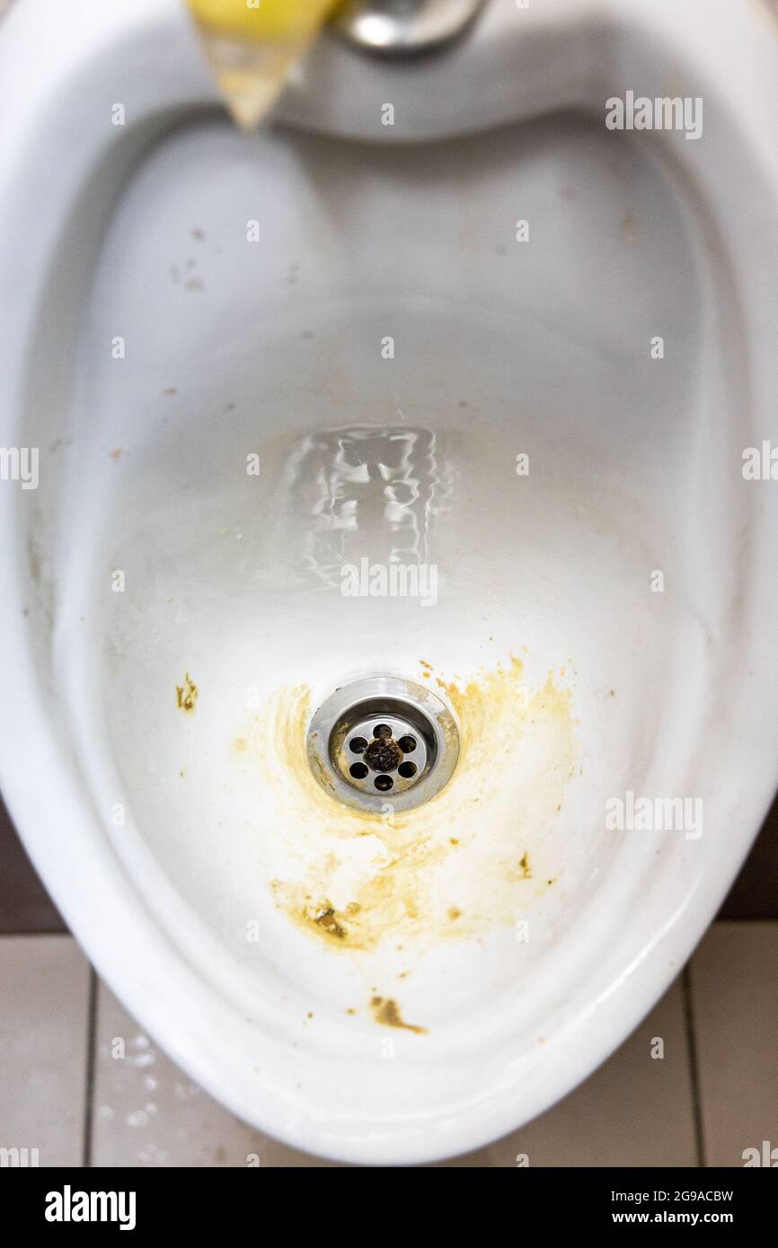 Close-up of dirty and smelly urinal bowl with limescale stain deposits ...