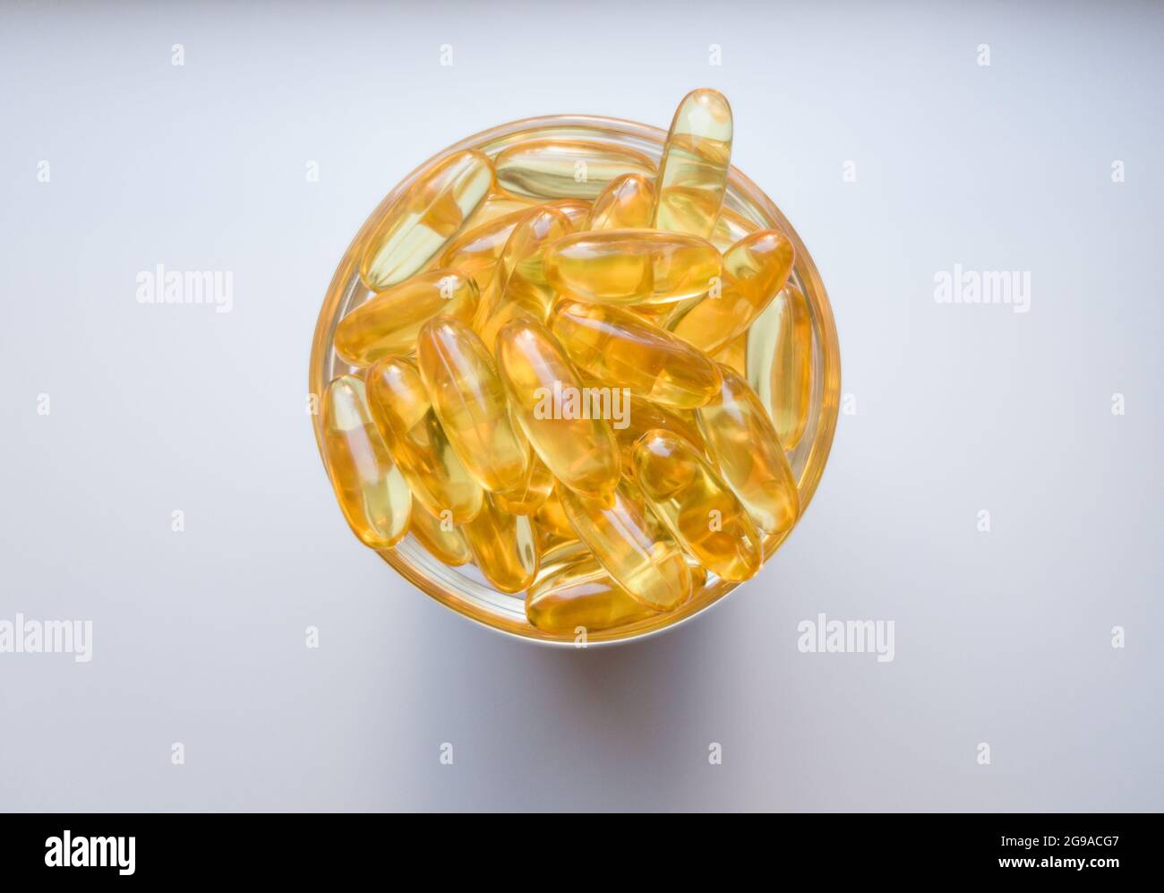 Fish oil capsules on a glass plate. A lot of vitamin omega 3 on a white ...