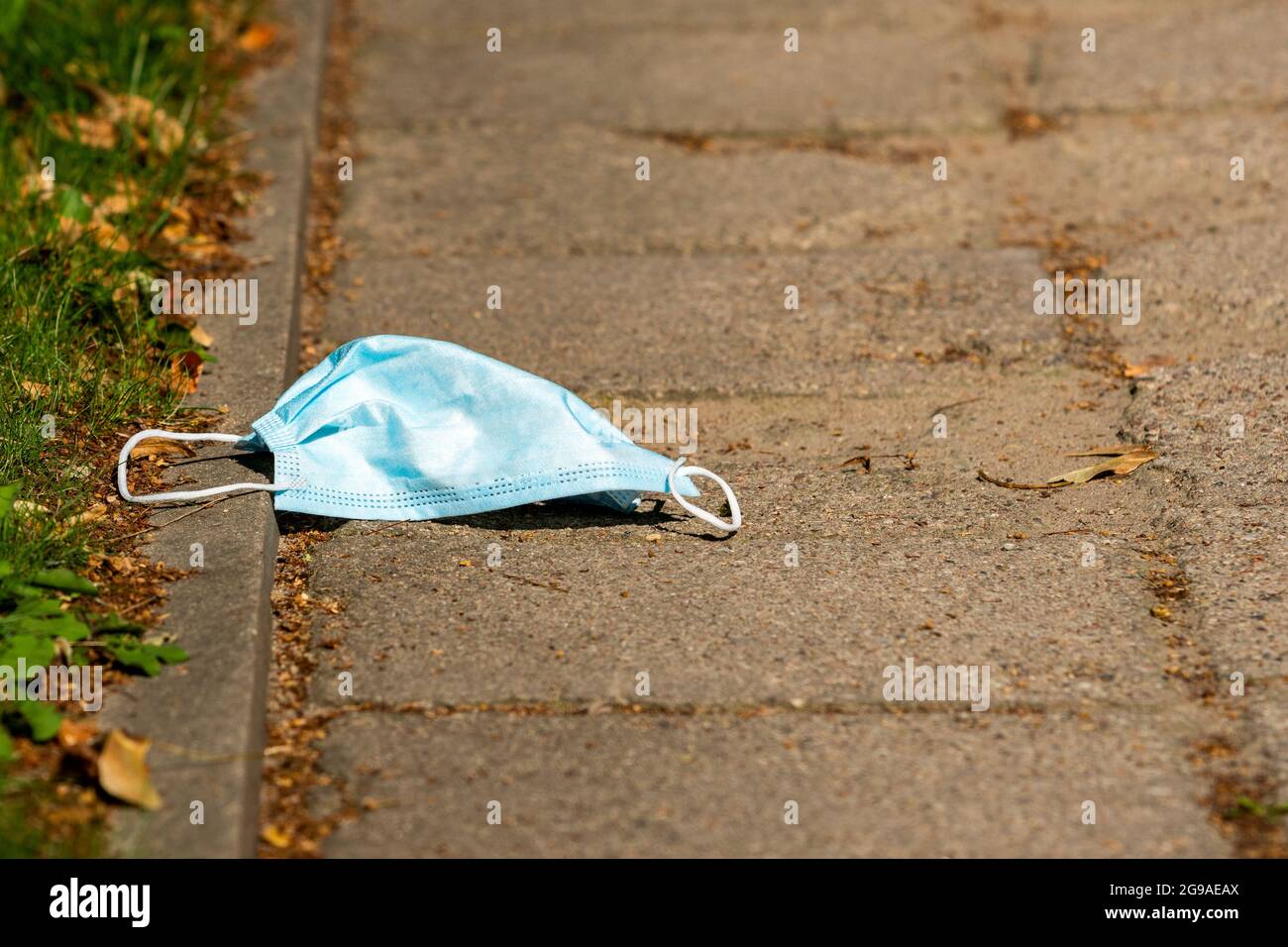 Disposable face mask dropped on the street. Dirty medical mask lies on ...