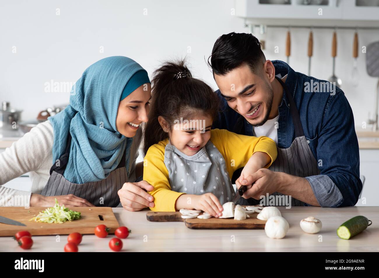 Cheerful Arabic Parents Showing Their Little Daughter How To Cook ...
