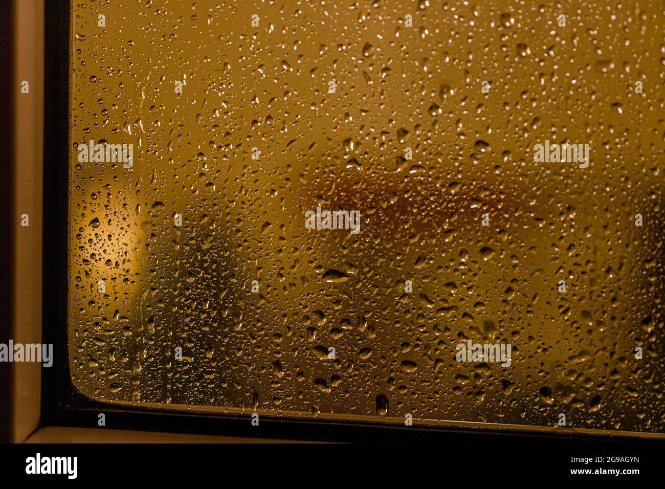 Close up of rain drops on the window in rainy night, warm lights and ...