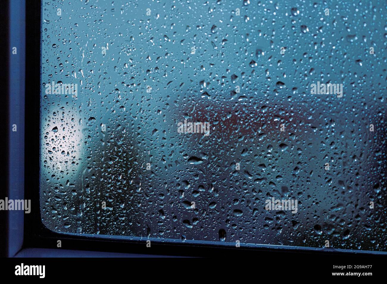 Close up of rain drops on the window in rainy night, cool lights and ...
